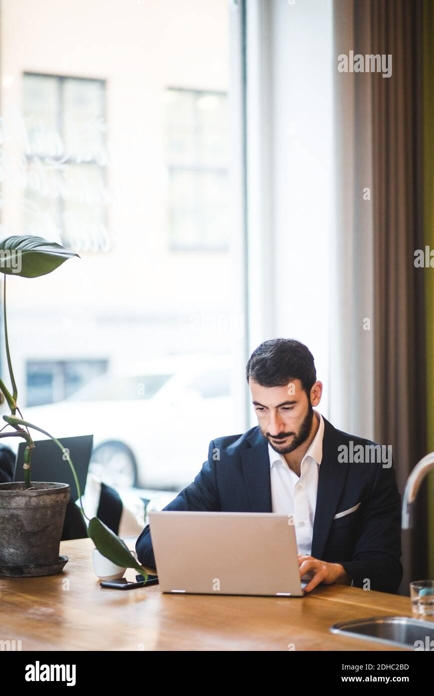 Male entrepreneur using laptop while sitting at table in office Stock ...