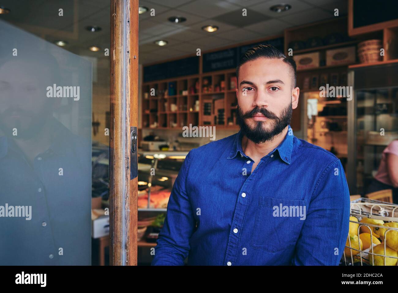 Portrait of confident sales clerk standing at store entrance Stock ...