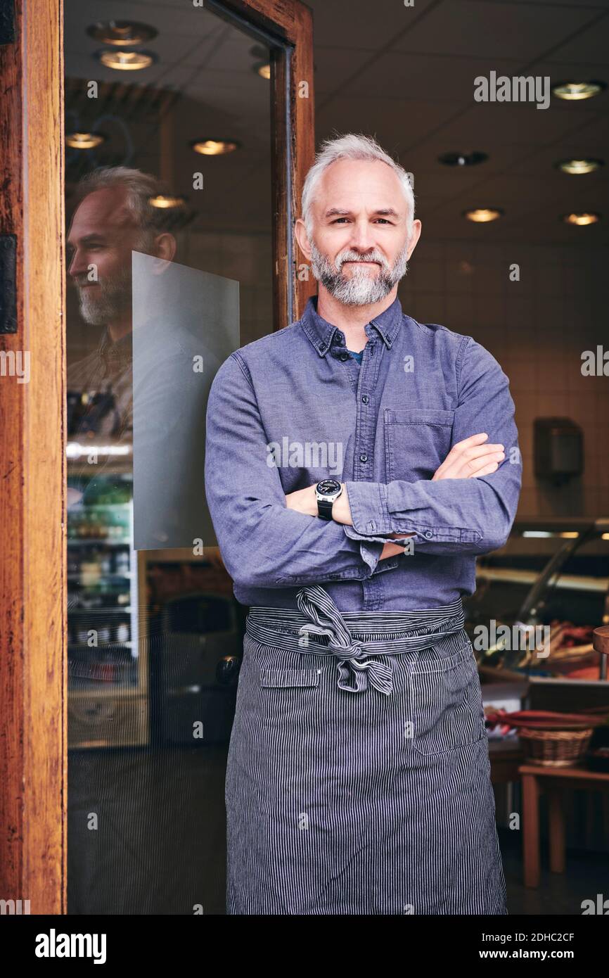 Portrait of confident salesman standing at store entrance Stock Photo ...