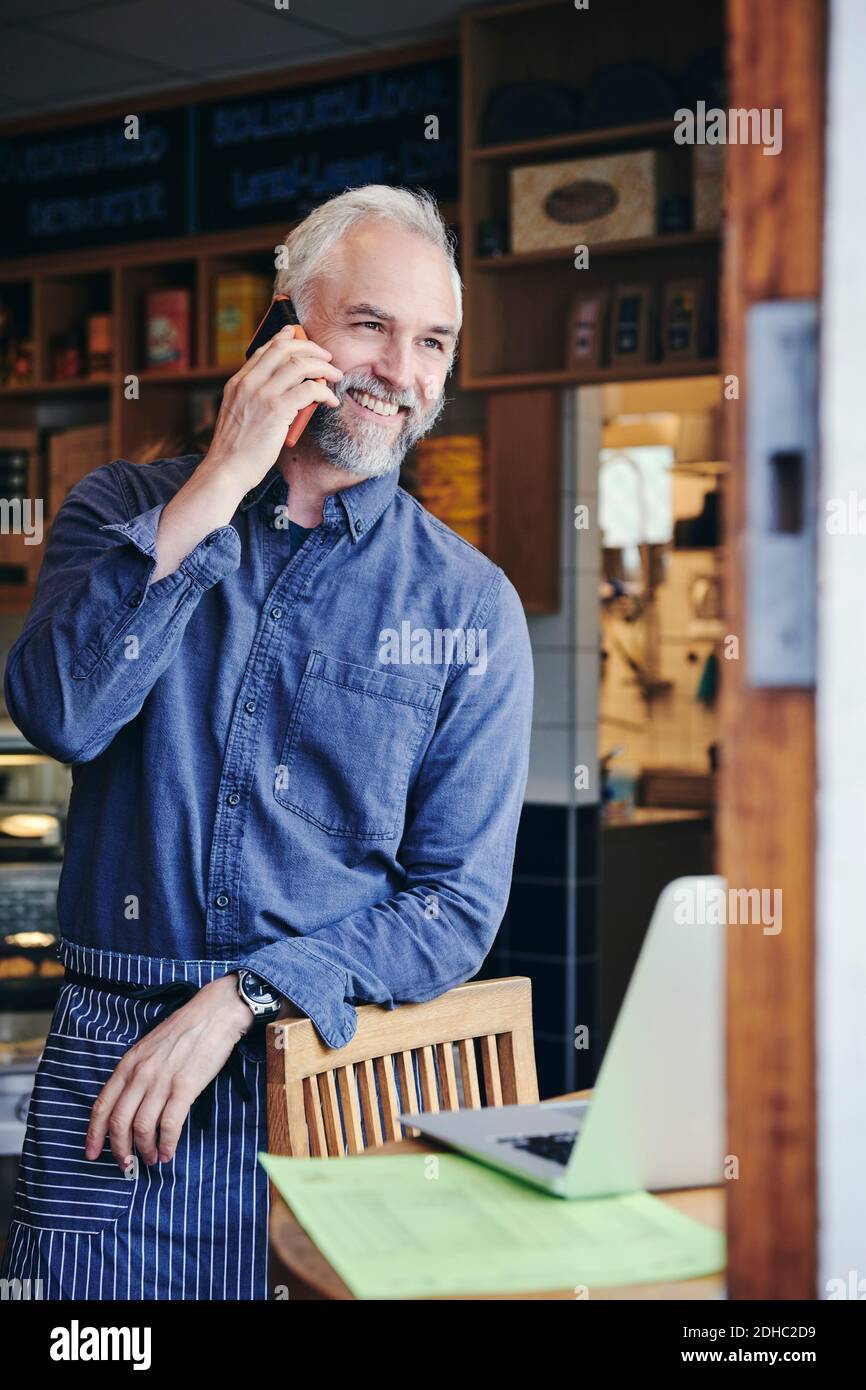 Sales clerk smiling while talking on mobile phone in deli Stock Photo ...