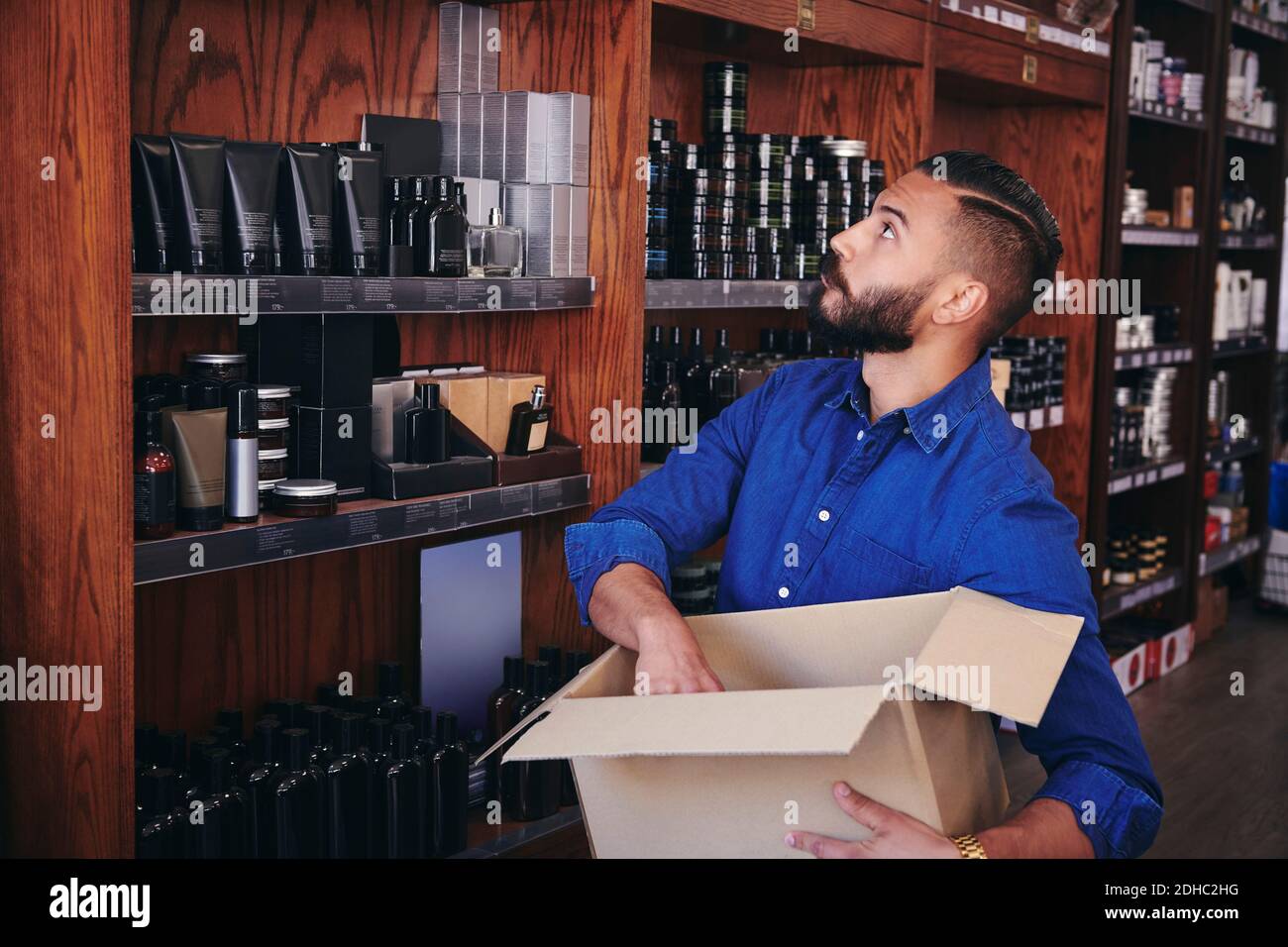 Salesman looking up while unpacking cardboard box in deli Stock Photo ...