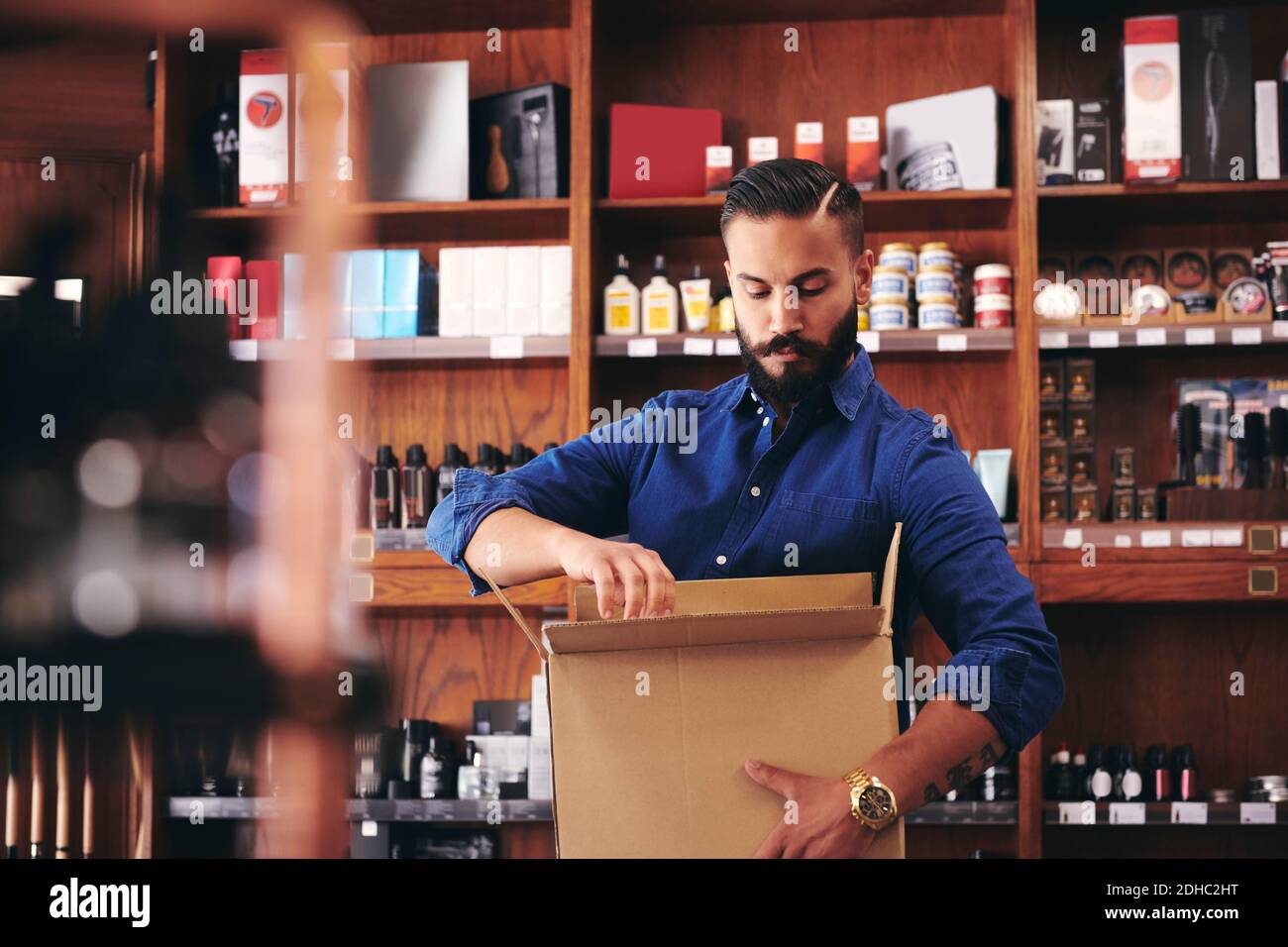 Salesman unpacking cardboard box while standing against rack in deli ...
