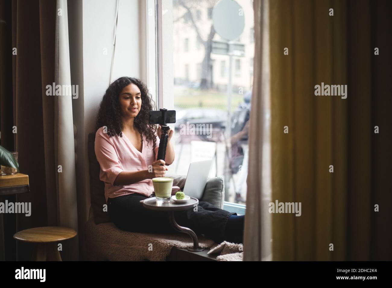 Confident young female influencer vlogging through smart phone on ...