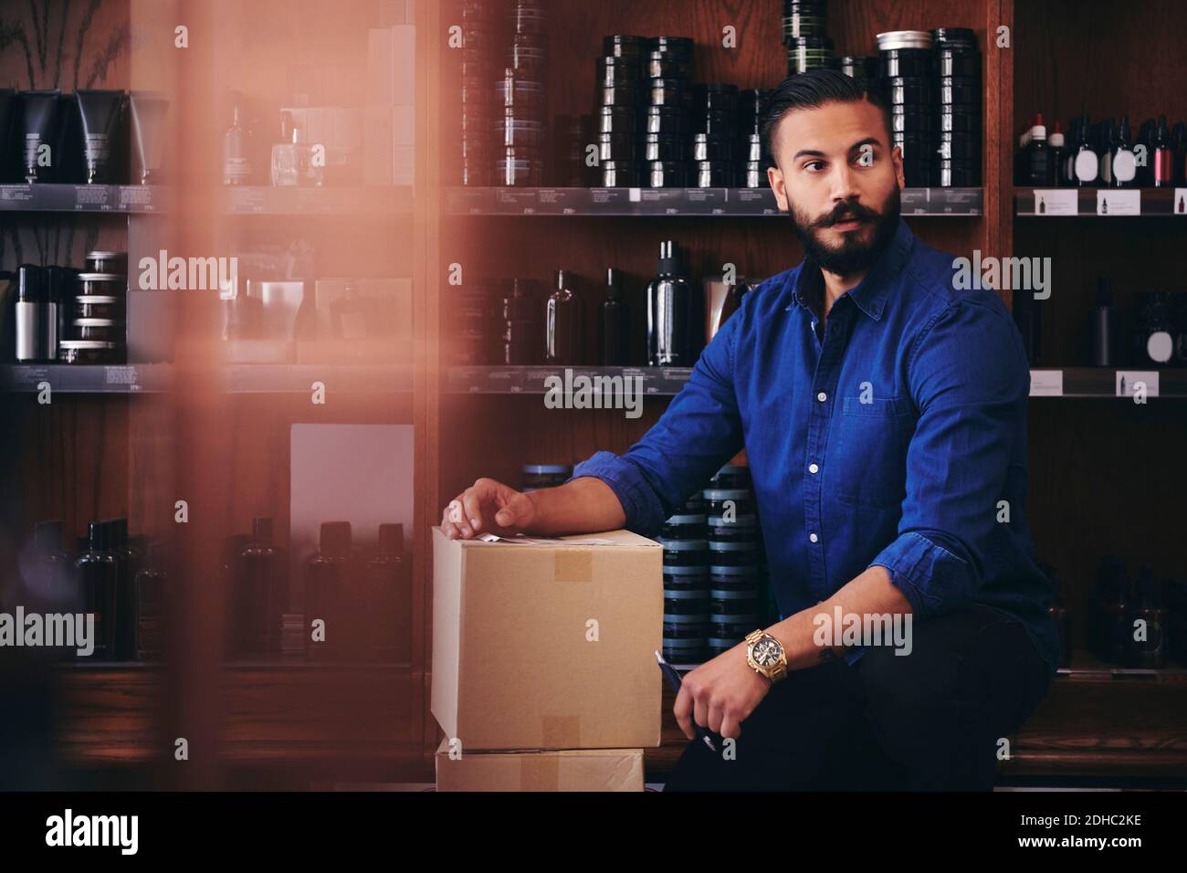Salesman looking away while kneeling by boxes in deli Stock Photo - Alamy
