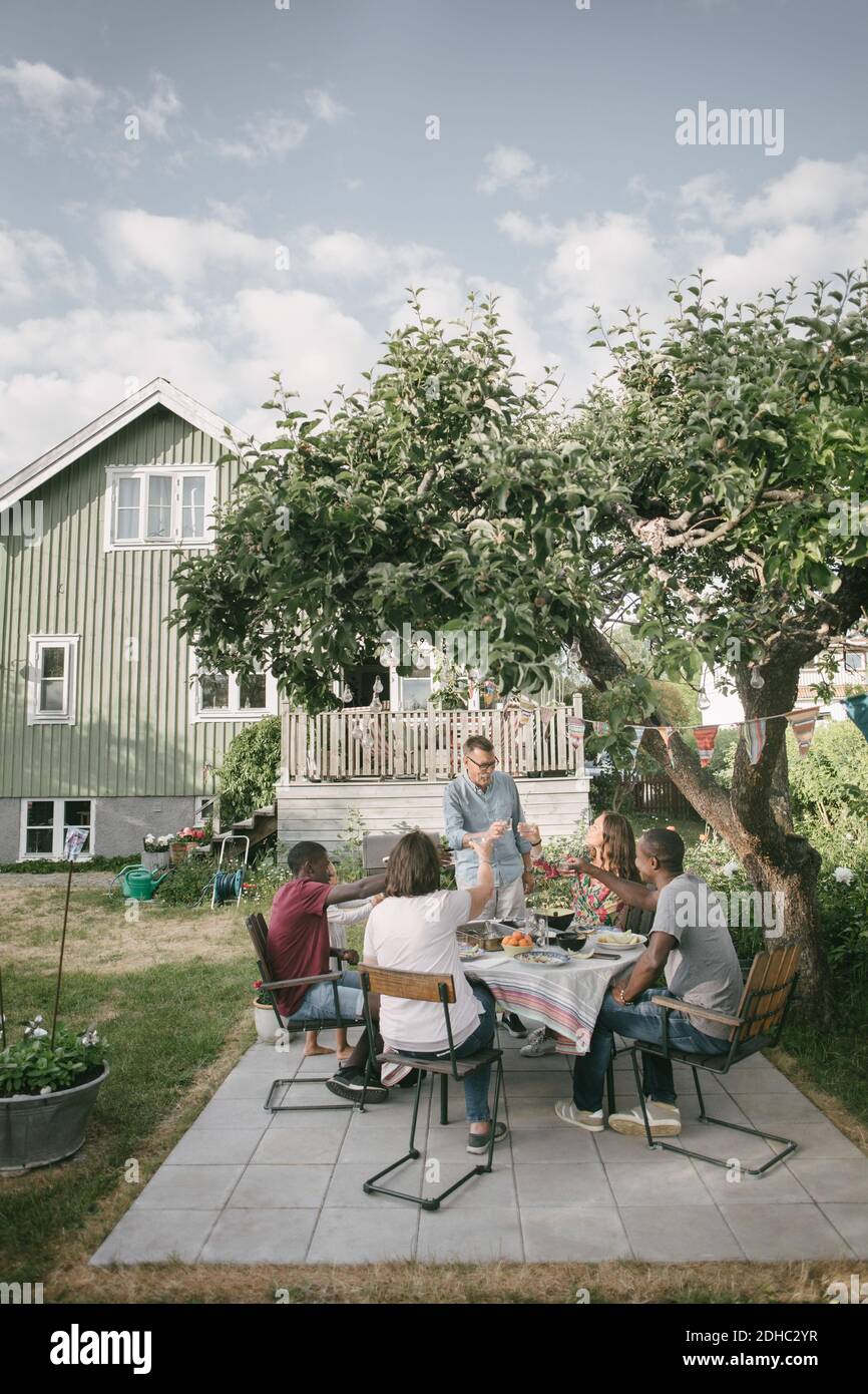 Multi-generational family toasting drinks at patio during garden party ...