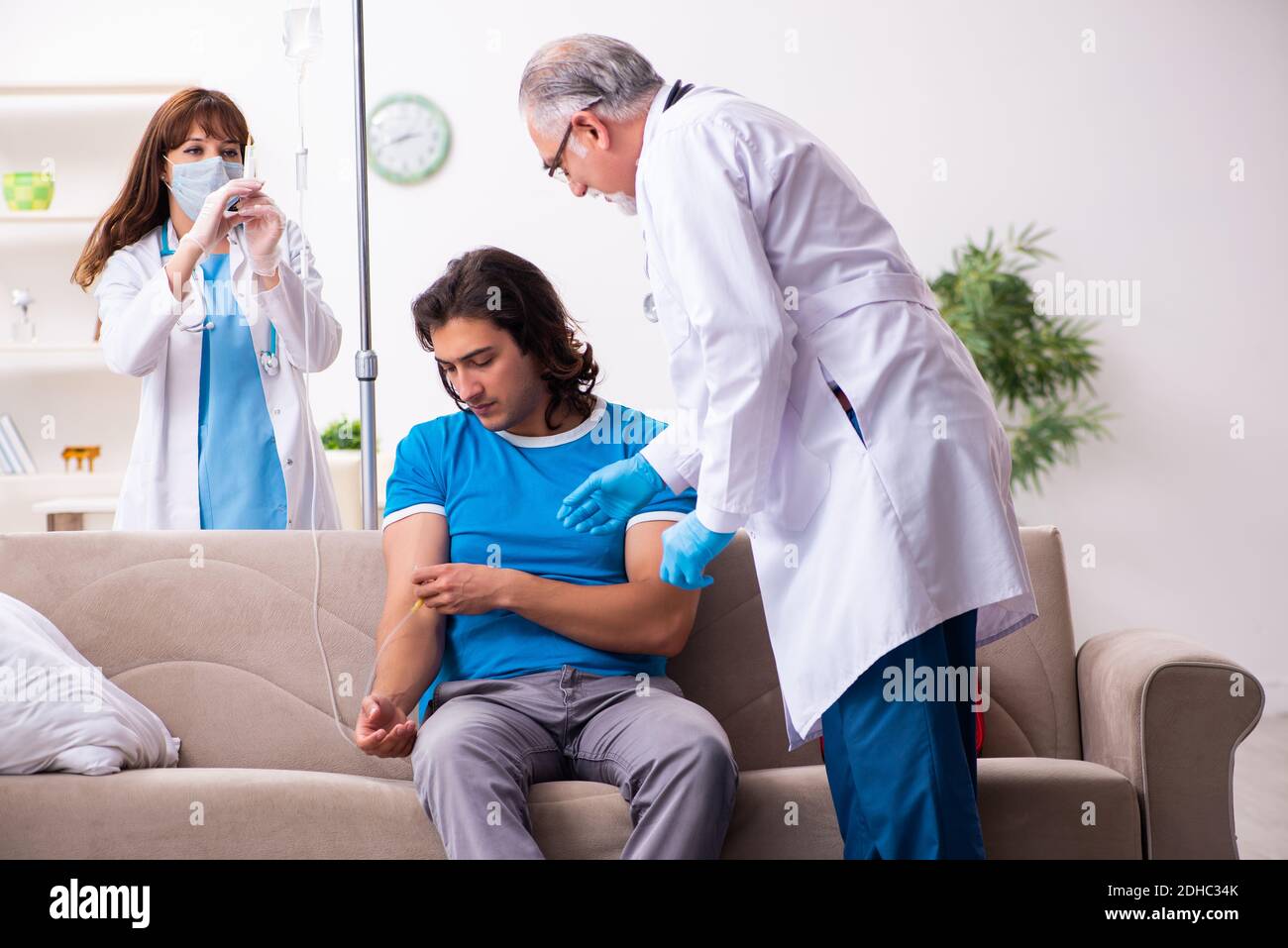 Two doctors visiting sick young man at home Stock Photo - Alamy