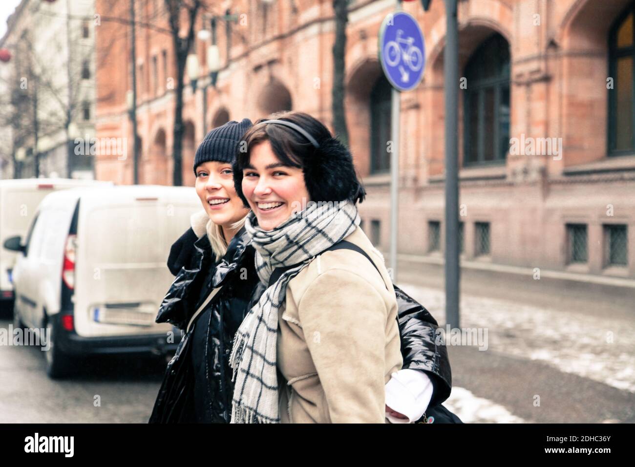 Portrait of cheerful young women wearing warm clothing while standing ... Portrait of cheerful young women wearing warm clothing while standing ...