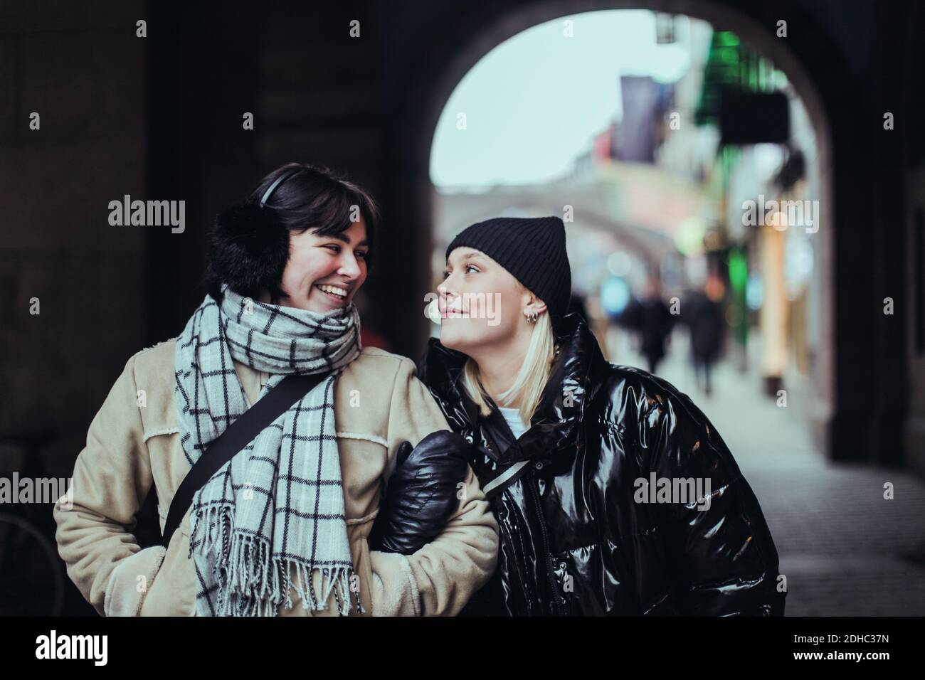 Smiling young female friends looking each other face to face while ...