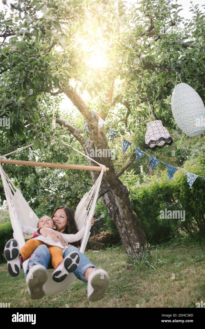 Mother and daughter smiling while swinging on hammock in backyard Stock Photo - Alamy