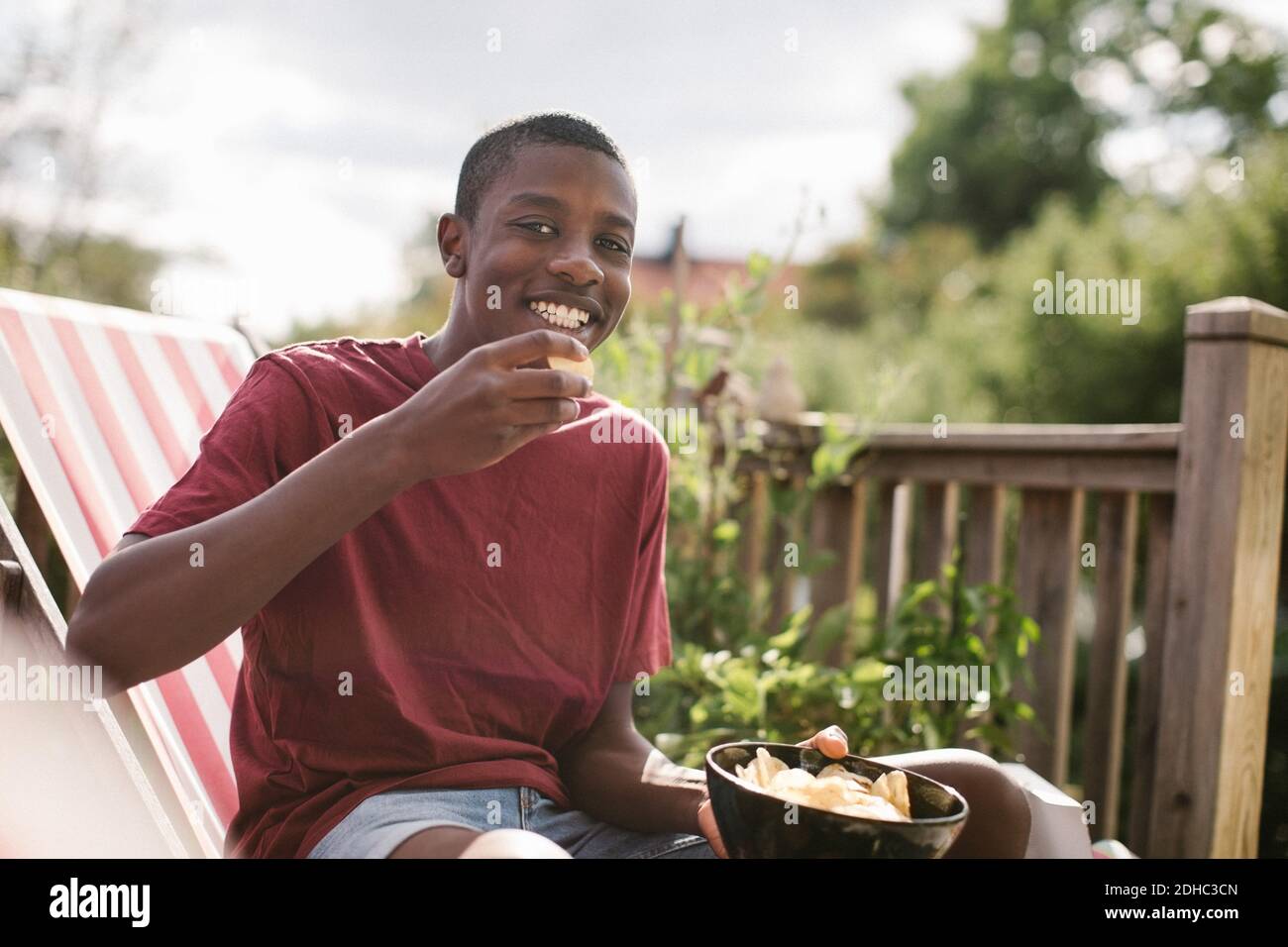 Portrait of smiling boy eating snack while sitting at porch Stock Photo ...