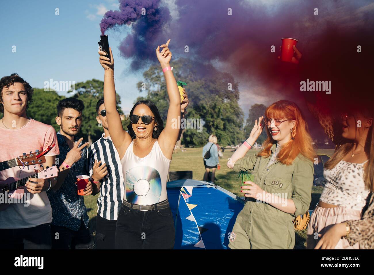 Woman holding distress flare while enjoying with friends during music ...