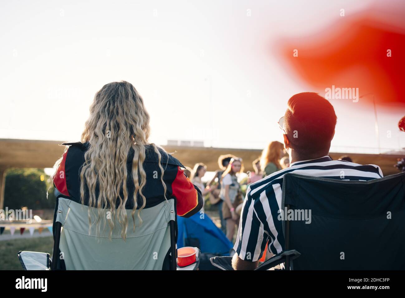 Rear view of man and woman looking at performers in music festival ...