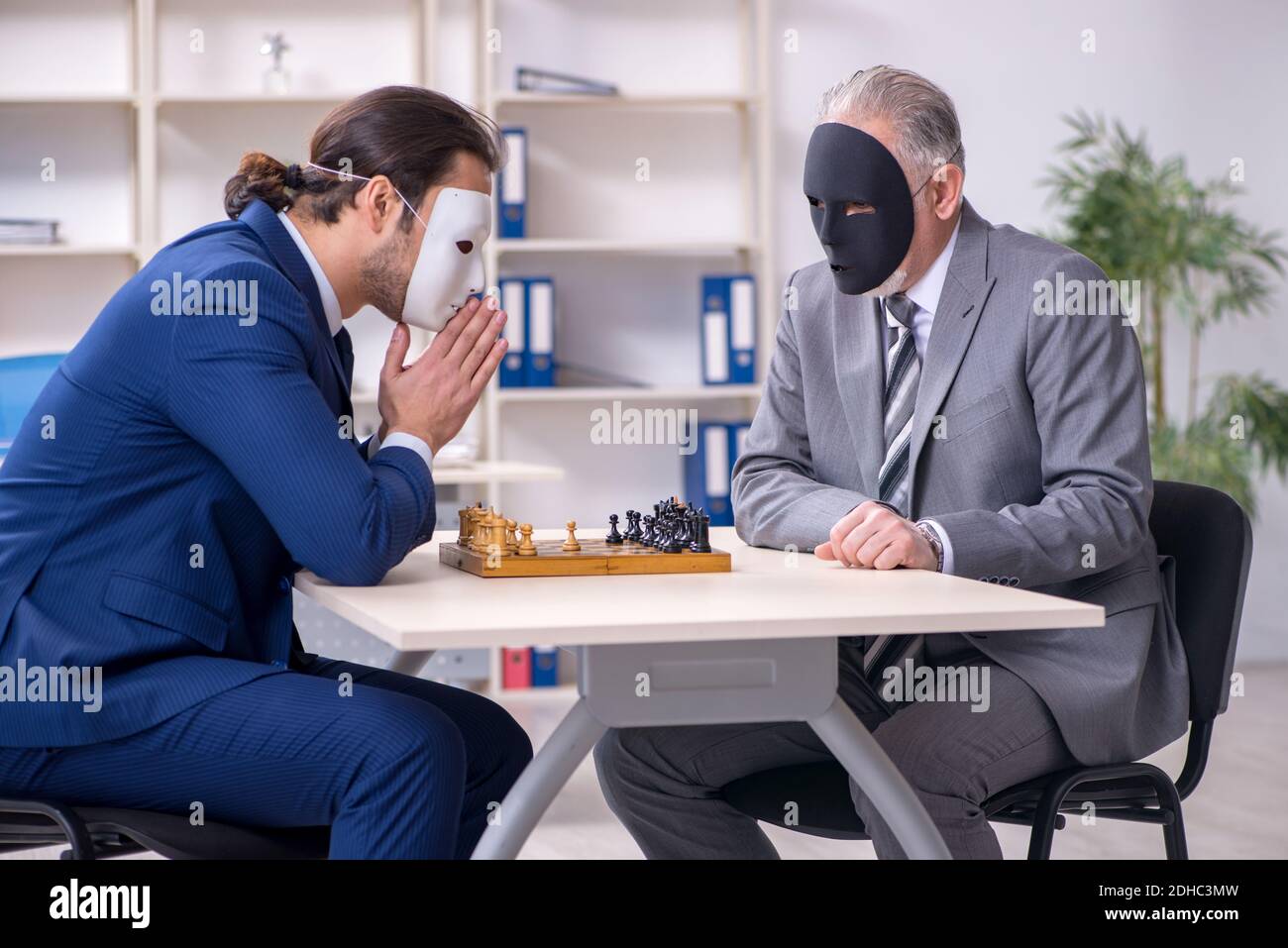 Two businessmen playing chess wearing masks Stock Photo - Alamy