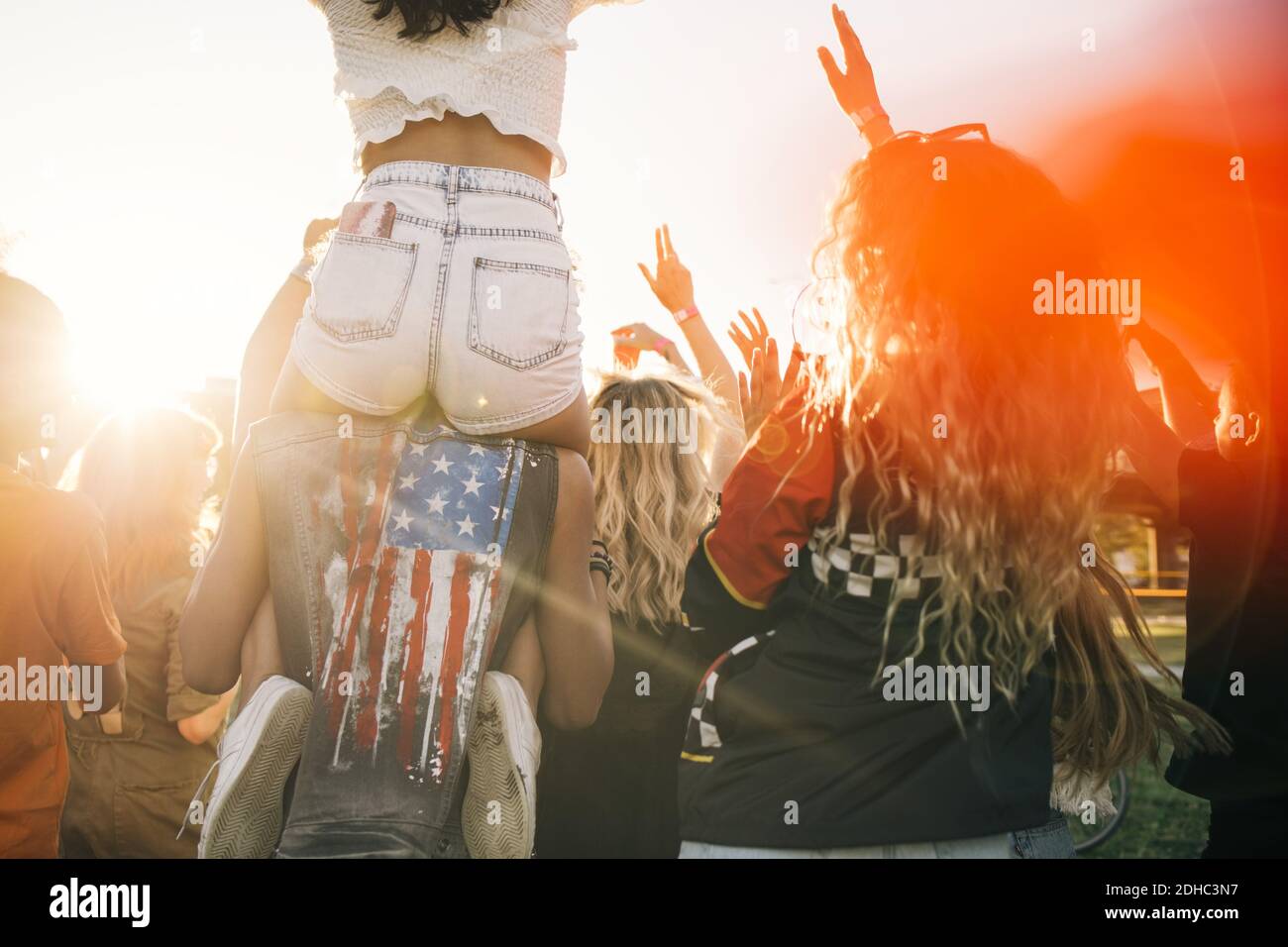 Man carrying friend on shoulder while enjoying in crowd at music event ...