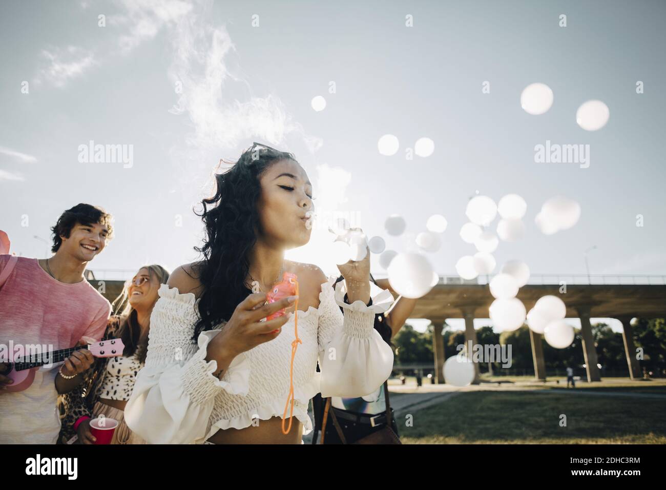 Young woman making smoke bubbles while enjoying with friends at music concert Stock Photo - Alamy