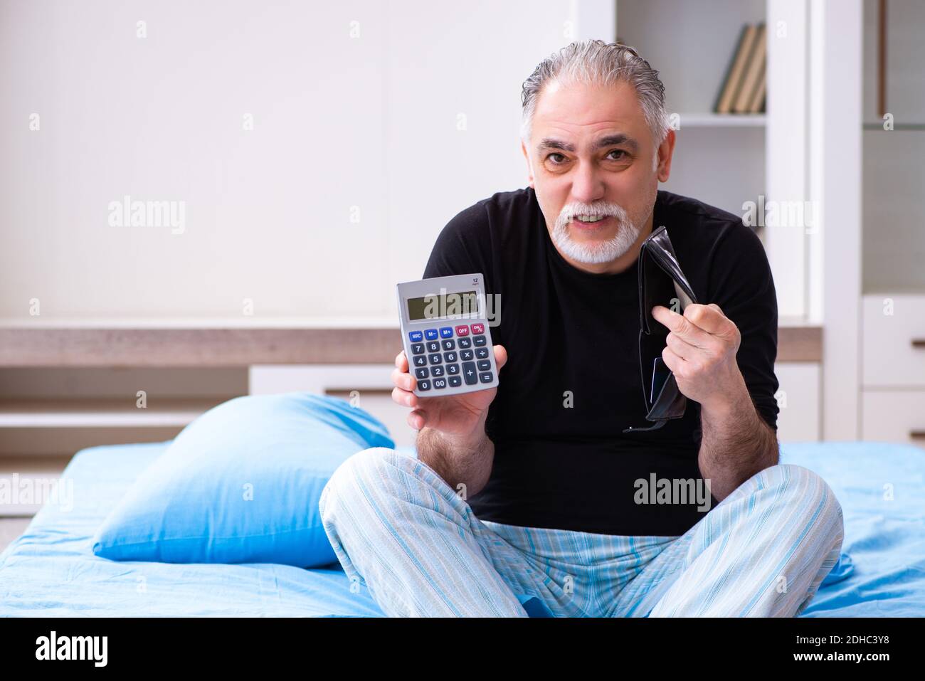 Old man in bankruptcy concept in the bedroom Stock Photo - Alamy