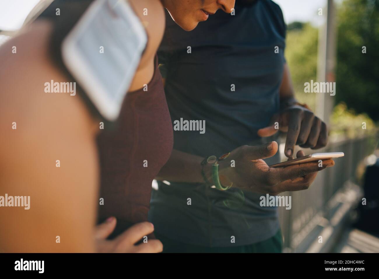 Midsection of sportsman showing mobile phone to female athlete while ...