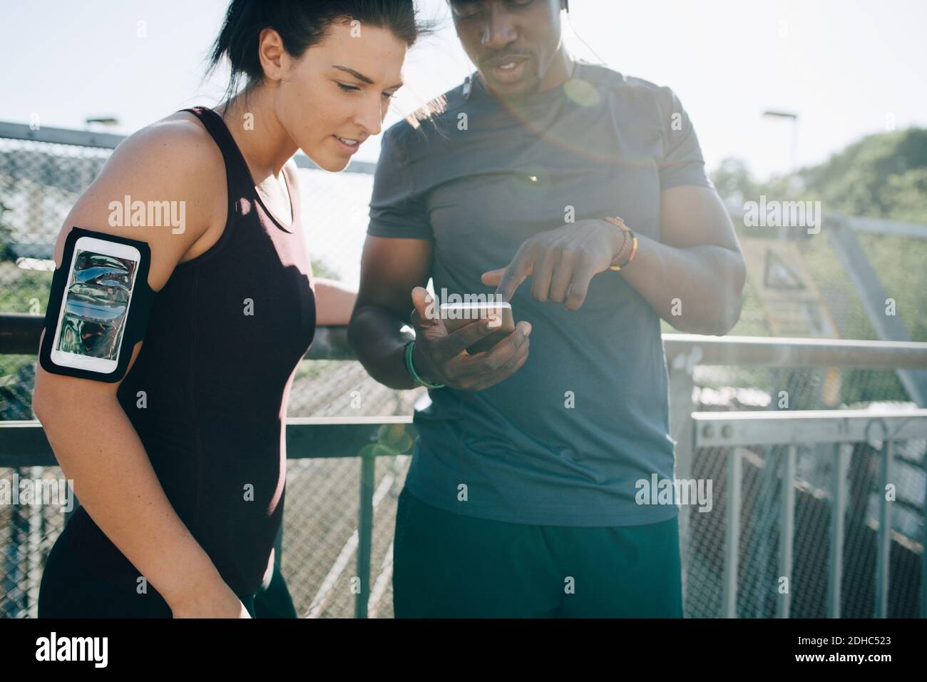 Sportsman showing mobile phone to female athlete while standing by ...