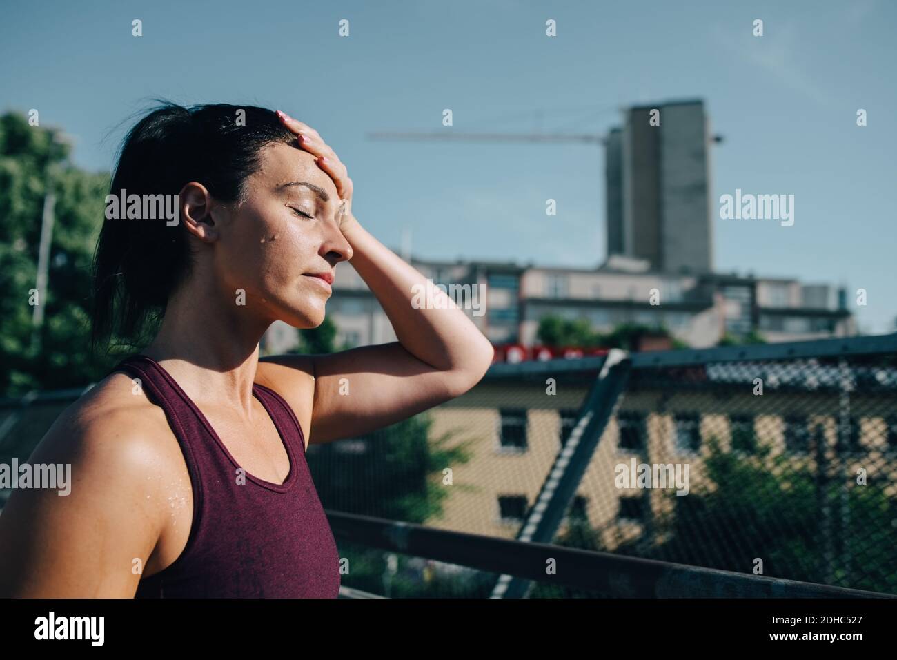 Exhausted sportswoman wiping sweat on forehead during sunny day Stock ...