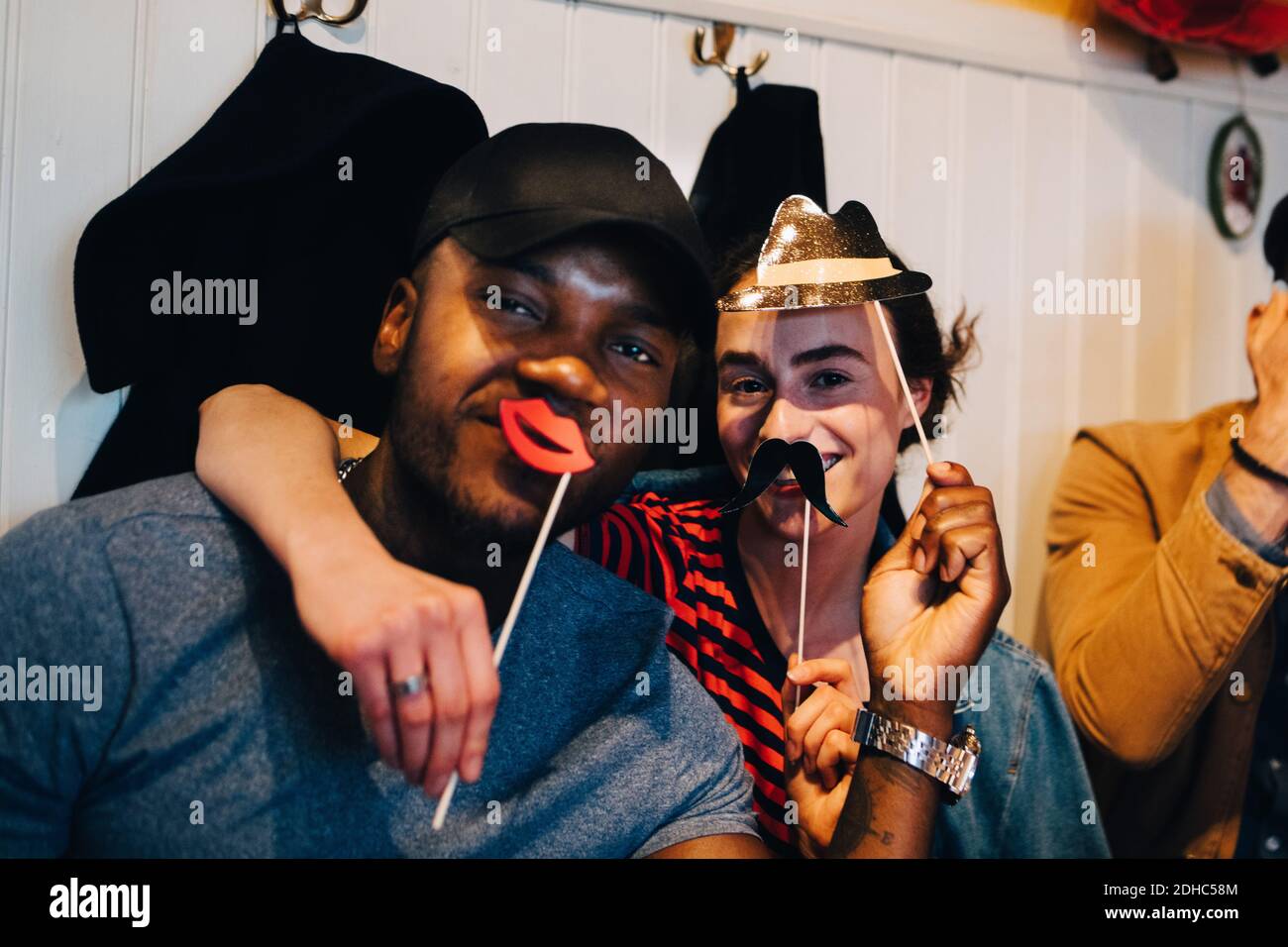 Portrait of smiling young friends holding props while sitting at ...