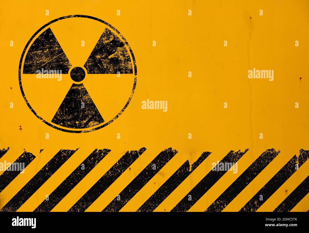 Black radioactive hazard warning sign painted over grunge yellow metal ...