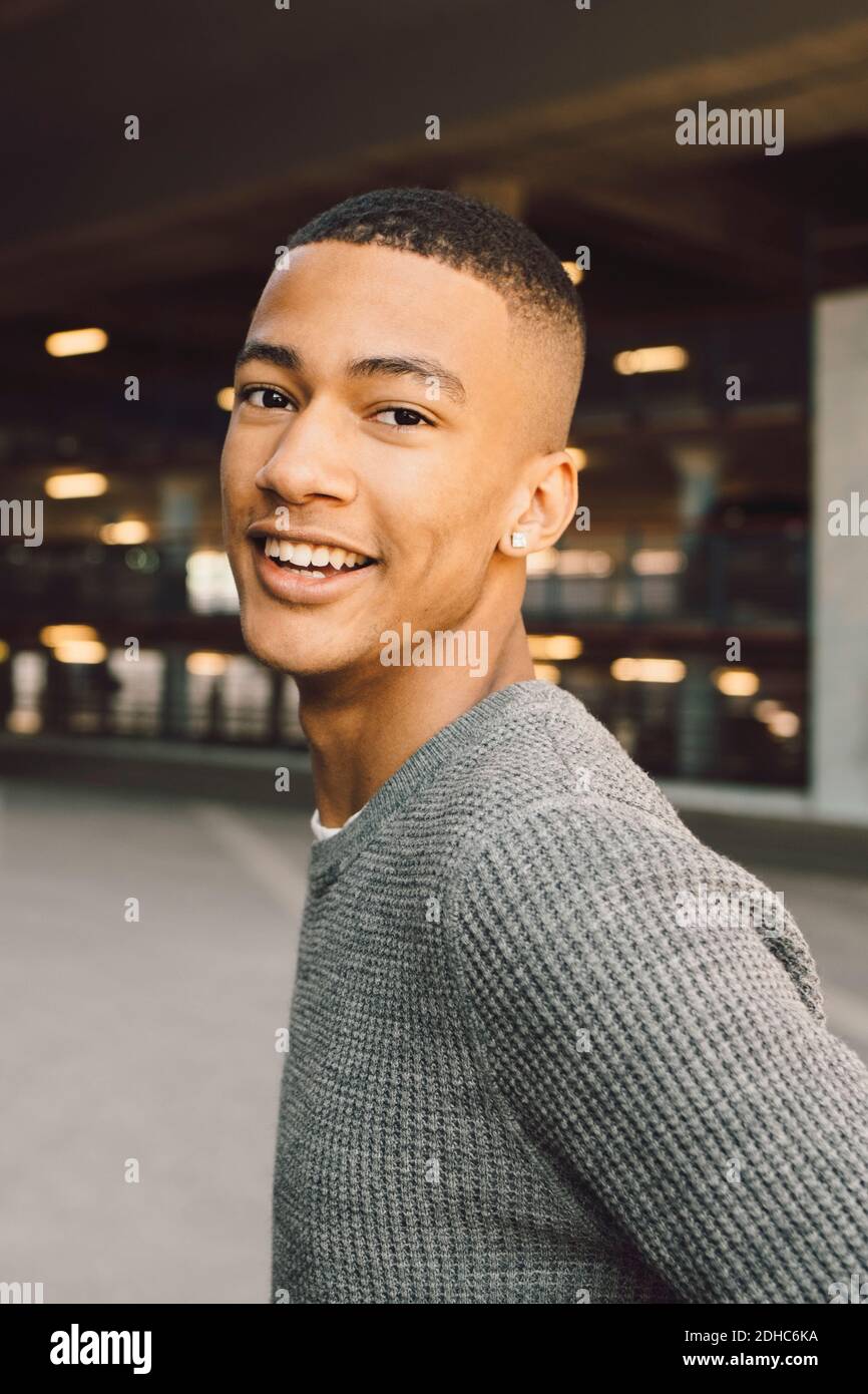 Side view portrait of smiling teenage boy standing in city Stock Photo ...
