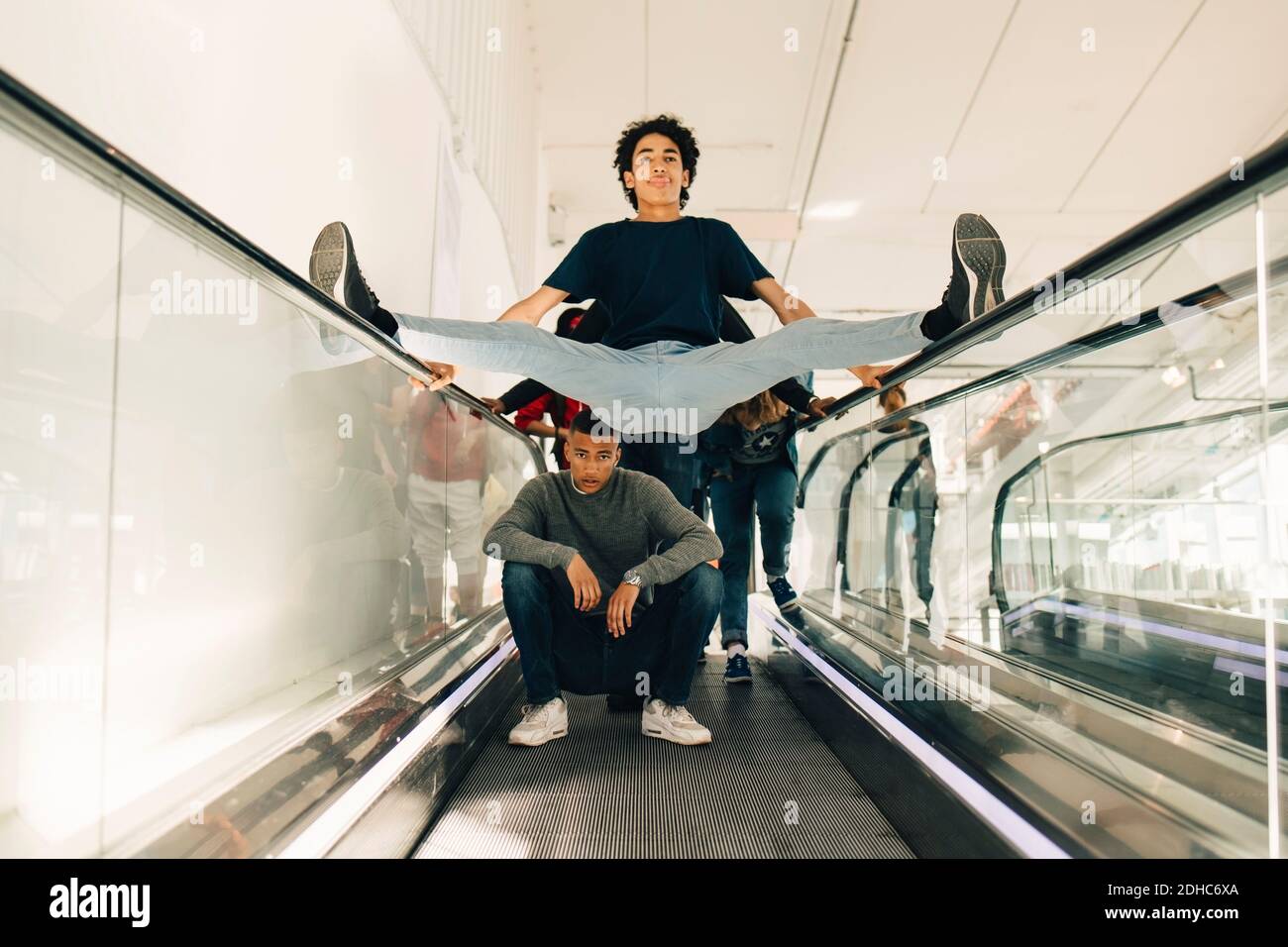 Playful male friends on moving walkway in shopping mall Stock Photo - Alamy