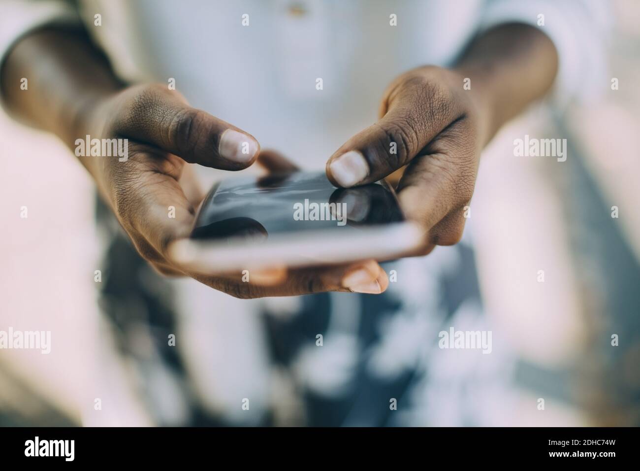 Midsection of young woman using smart phone while standing outdoors ...