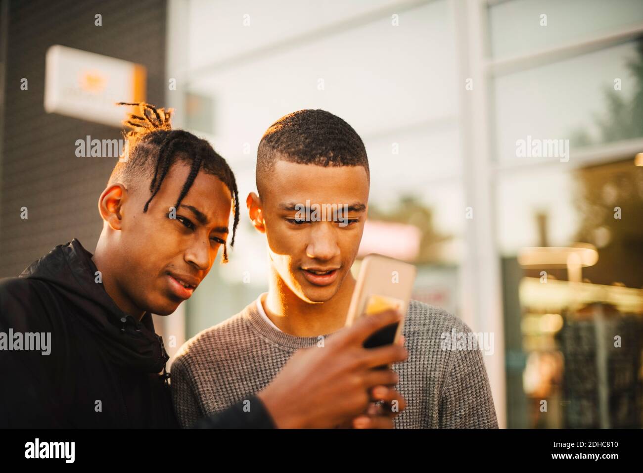 Teenage boy showing mobile phone to friend in city during sunset Stock ...