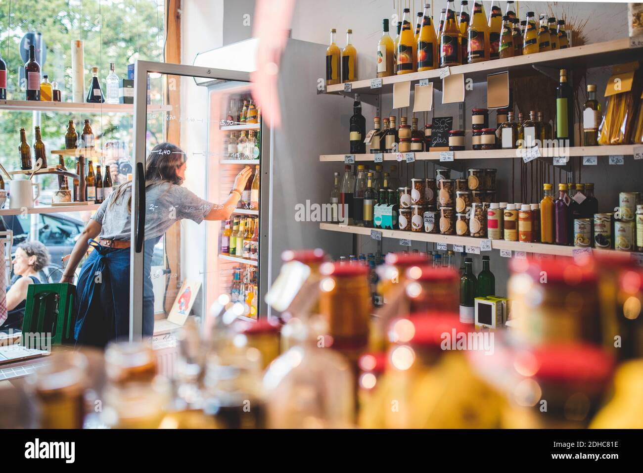 Female employee arranging bottles in refrigerator at deli Stock Photo ...