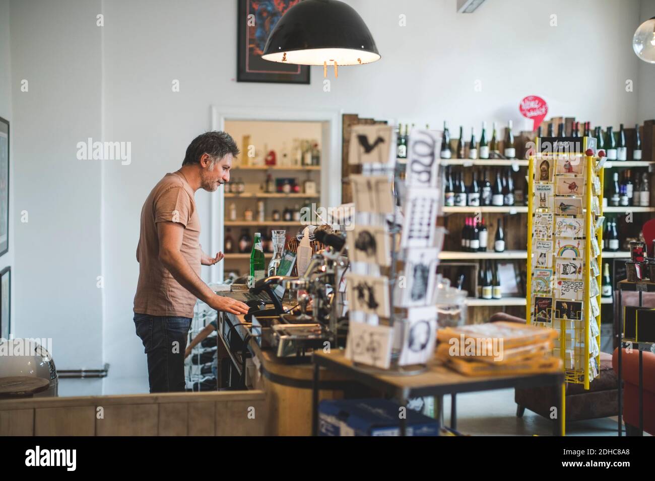 Side view of male sales clerk standing at checkout counter in deli ...