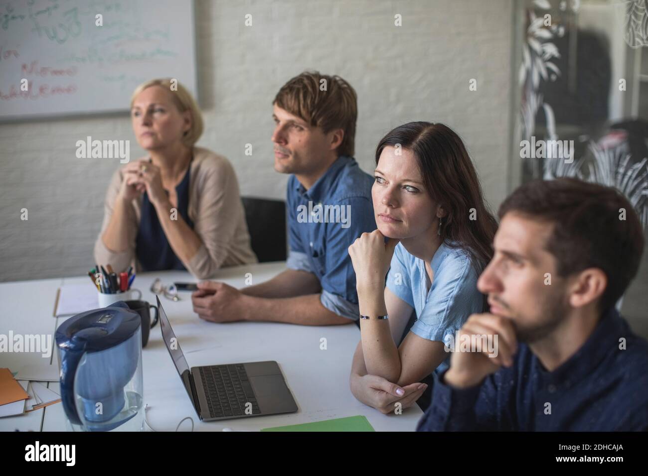 Serious creative business people listening while sitting in conference ...
