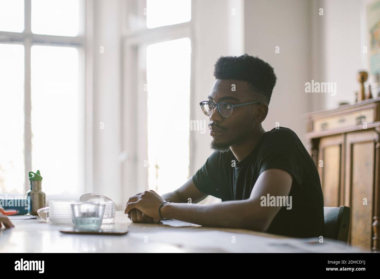 Young man sitting table hi-res stock photography and images - Alamy