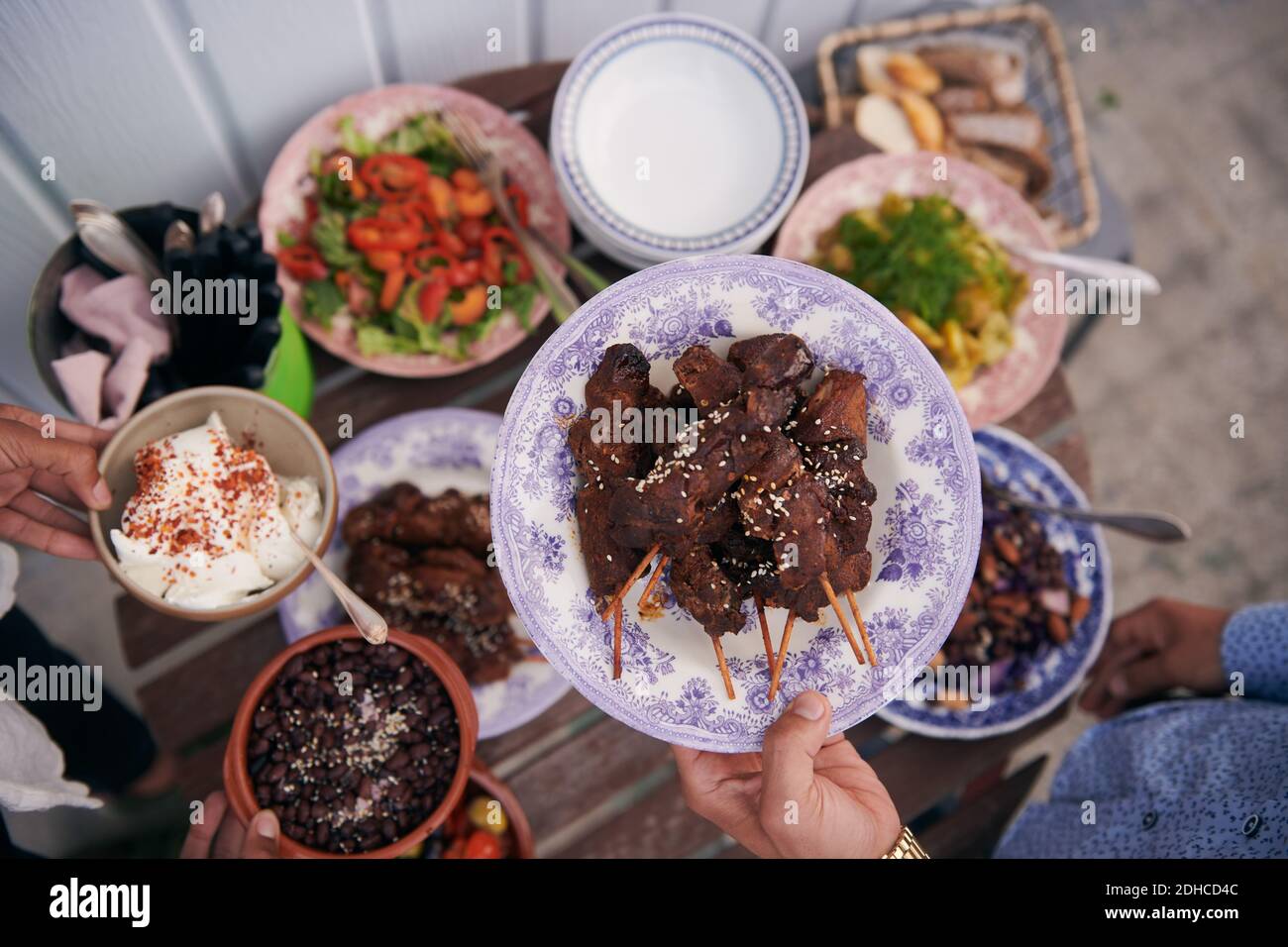 High angle view of man's hand holding cooked meat at buffet during ...