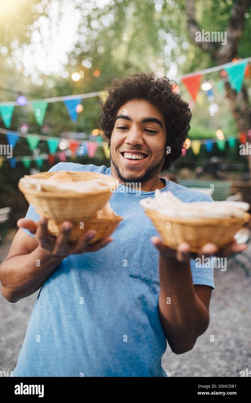 Smiling young man carrying food in bowls during garden party Stock ...