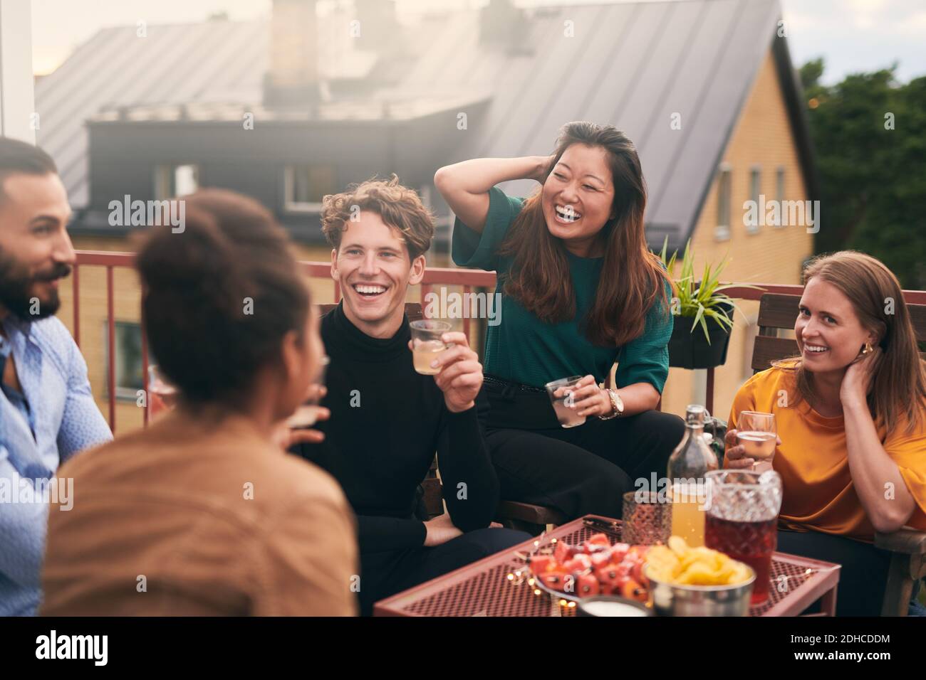 Cheerful friends talking while enjoying social gathering on terrace ...