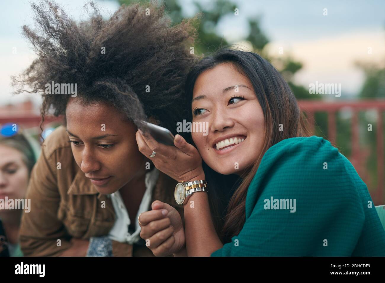 Friends listening mobile phone during social gathering on terrace Stock ...