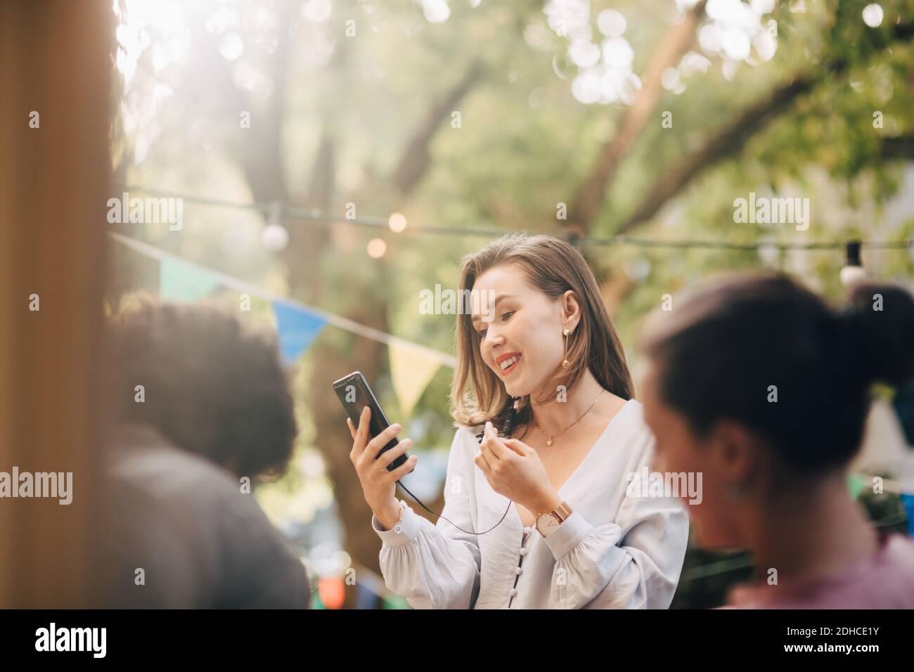 Smiling young woman video conferencing through mobile phone in balcony ...
