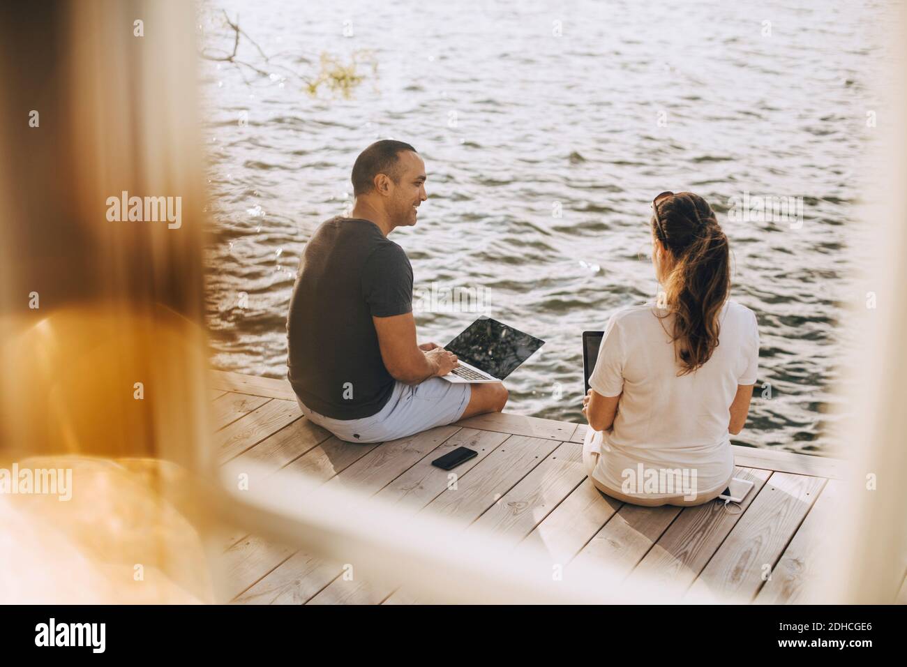 Couple talking while working at patio seen through window Stock Photo ...