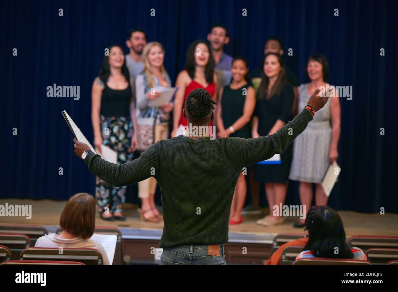 Conductor leading choir on stage in auditorium Stock Photo - Alamy