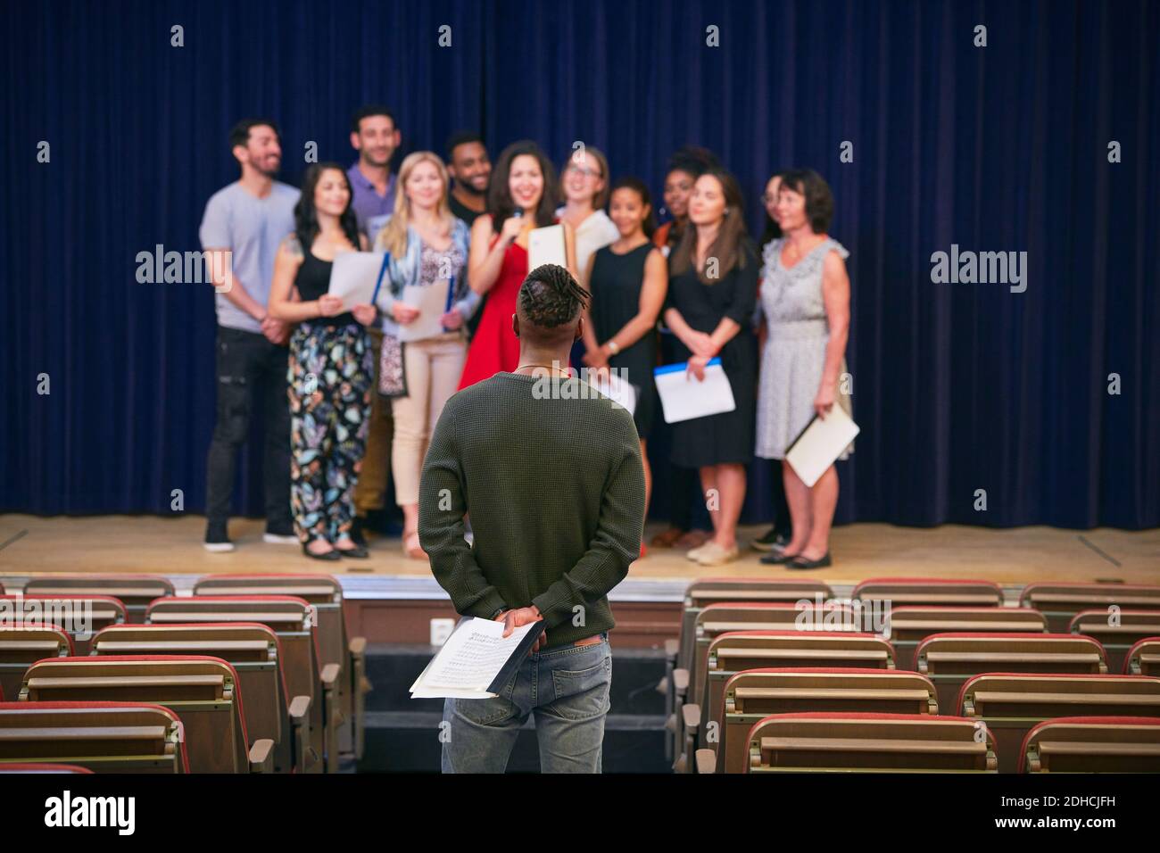 Musical teacher listening to choir on stage in auditorium of language ...