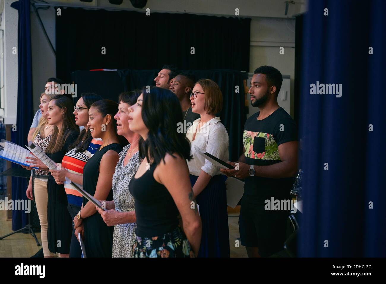Multi-ethnic group of students singing in choir at school auditorium ...