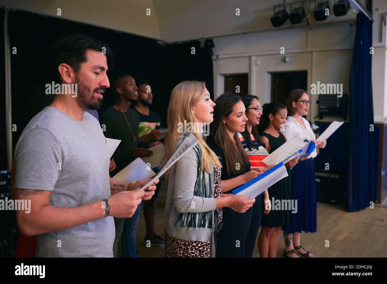 Male and female friends with music sheets singing at choir practice ...