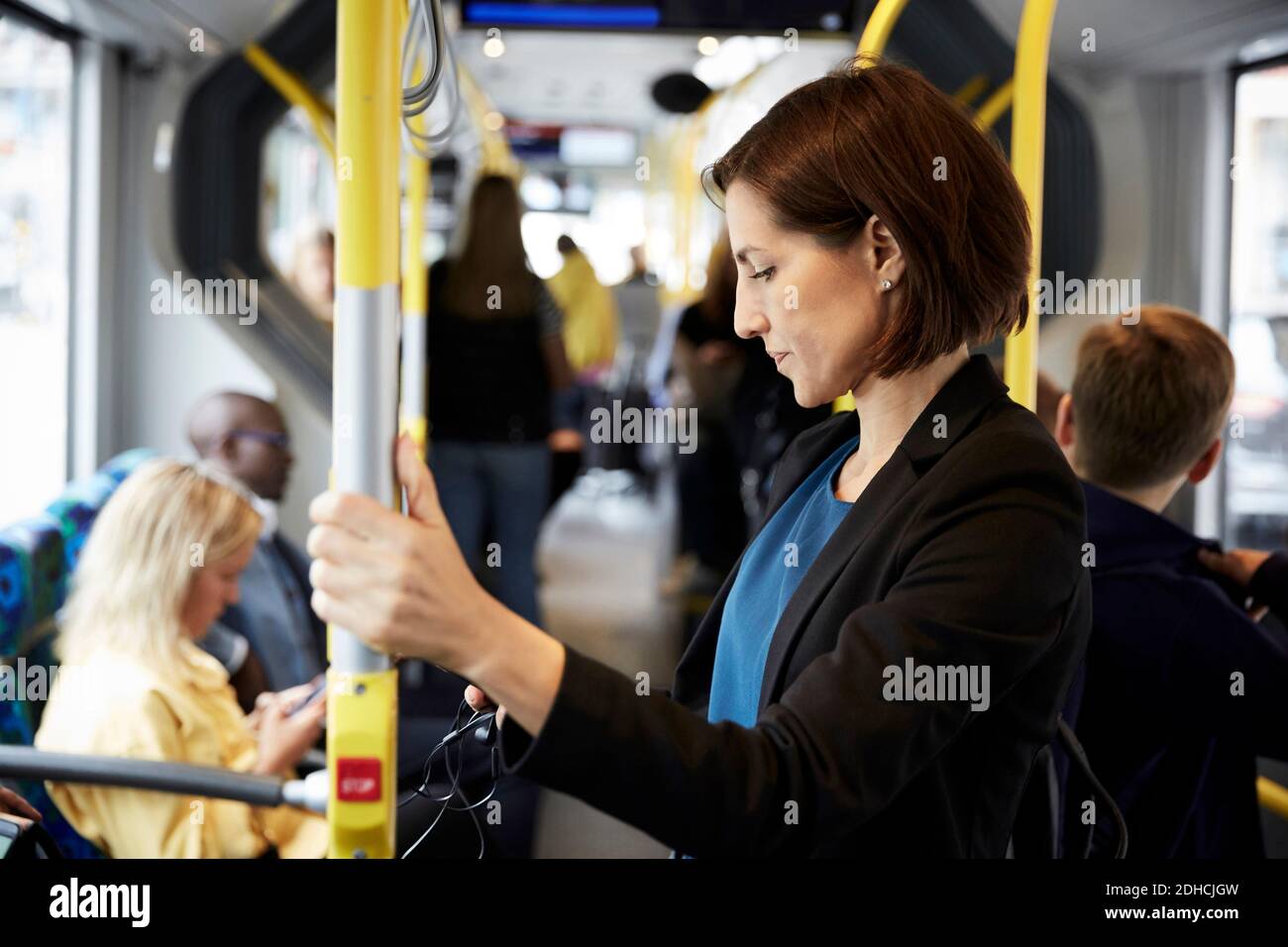 Side view of female commuter standing in bus Stock Photo - Alamy