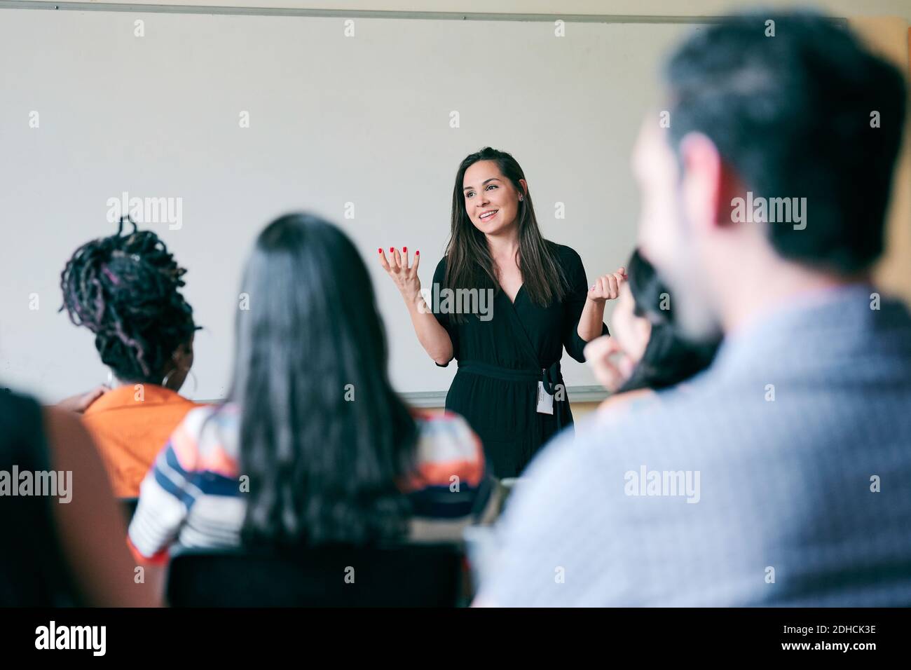 Happy teacher gesturing and explaining students in classroom Stock ...