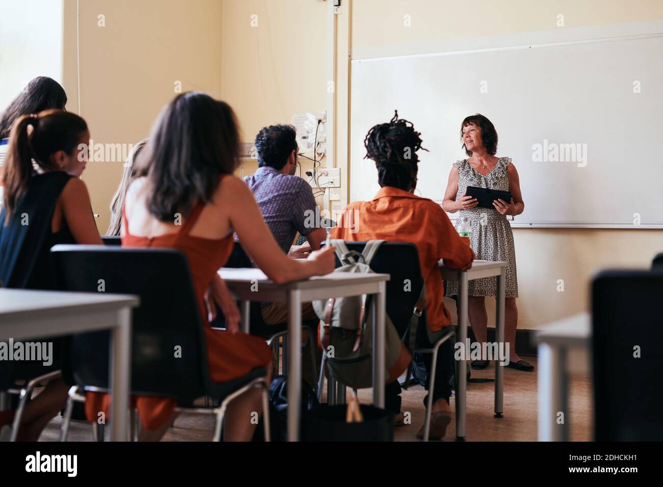 Teacher explaining to students in classroom Stock Photo - Alamy