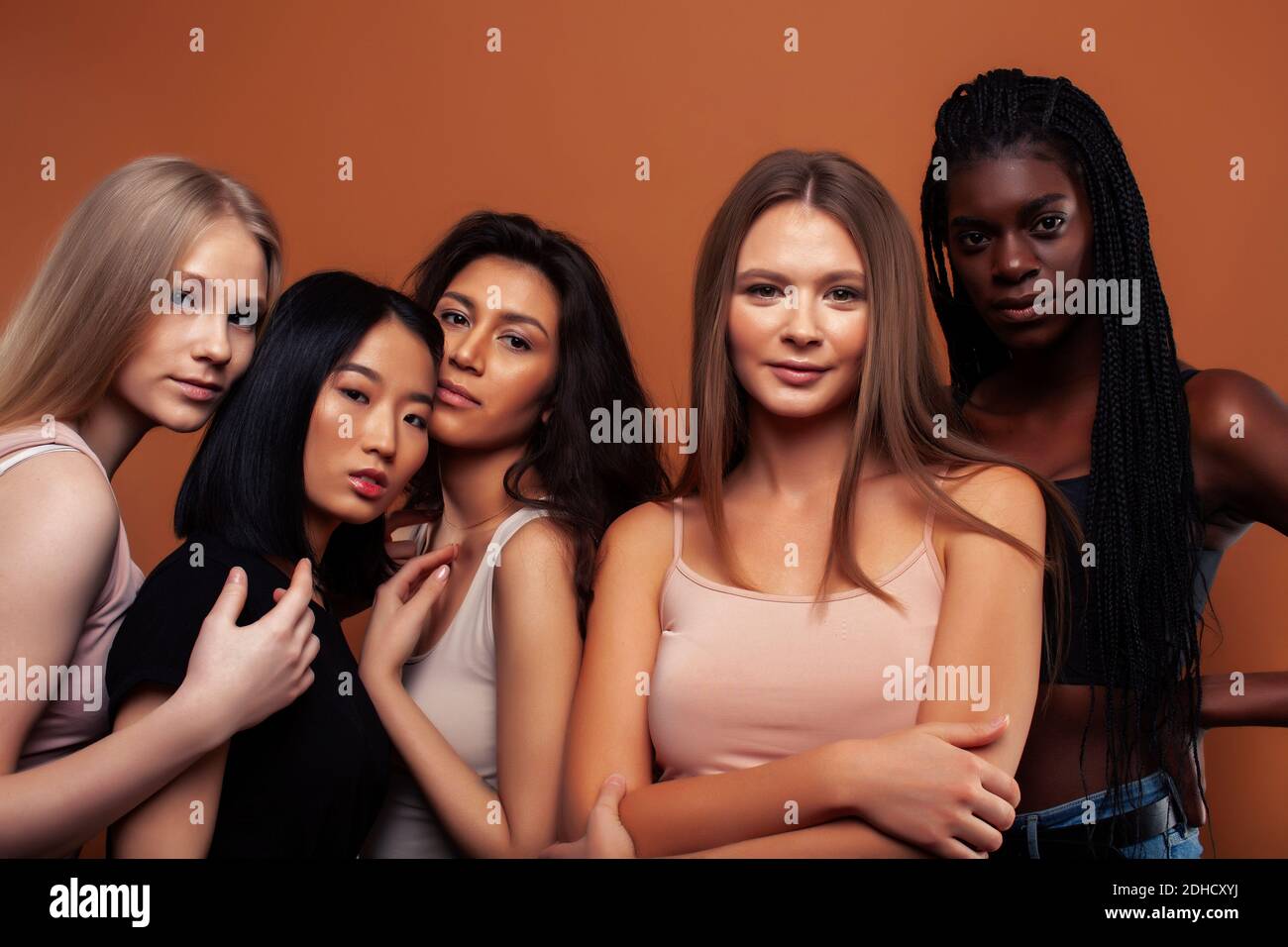 young pretty asian, caucasian, afro woman posing cheerful together on brown background ...