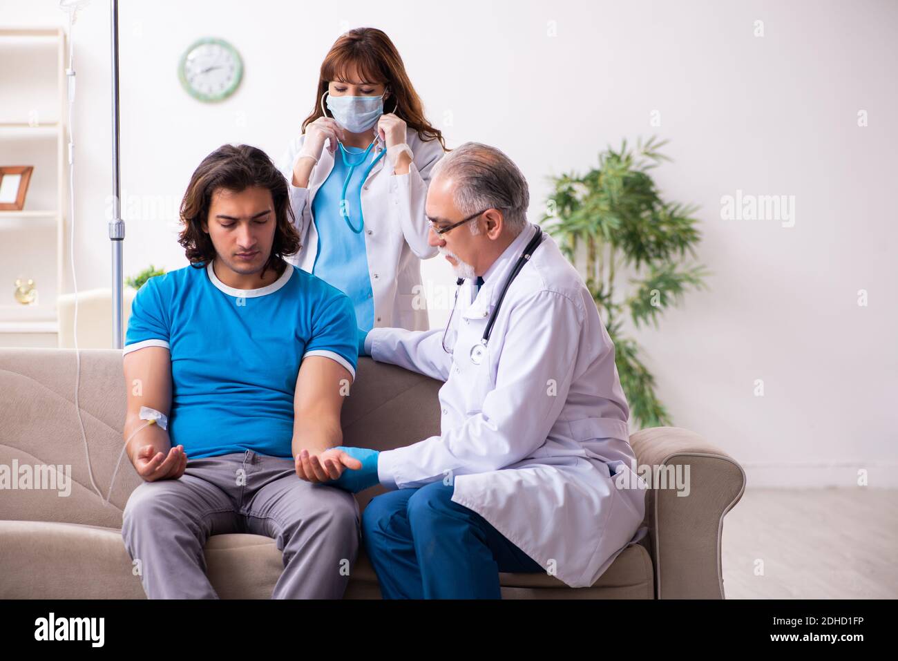 Two doctors visiting sick young man at home Stock Photo - Alamy