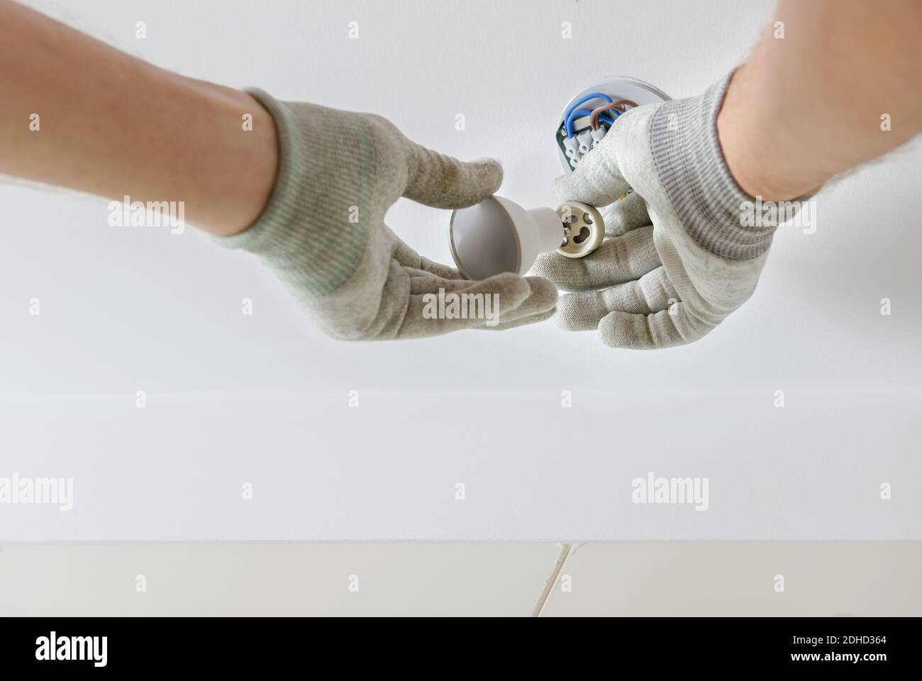 A worker is installing an LED spotlight on the suspended ceiling Stock ...