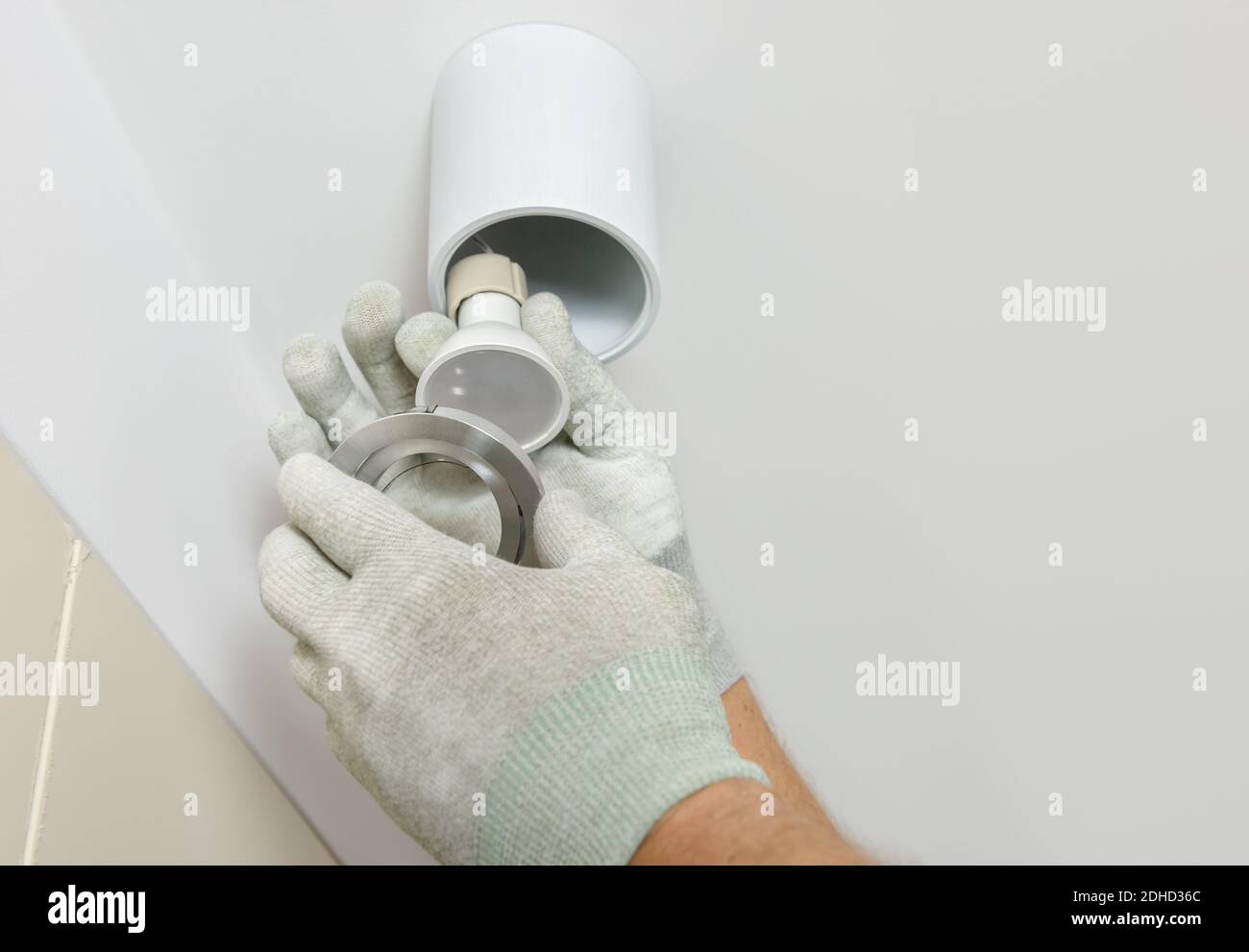 A worker is installing an LED spotlight on the suspended ceiling Stock ...